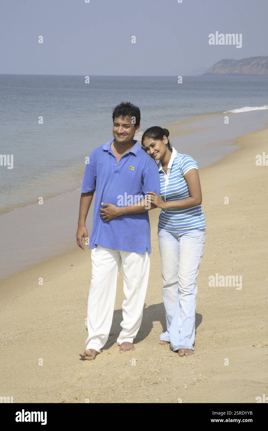 South Asian Indian young woman holding arm of man resting head on his shoulder standing on ...