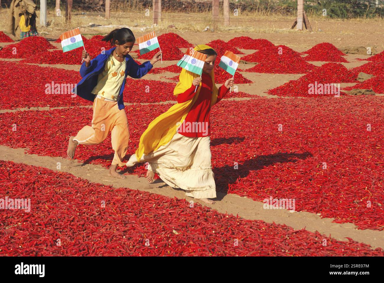 Girls running across red chilli pepper with national flags in hands ...