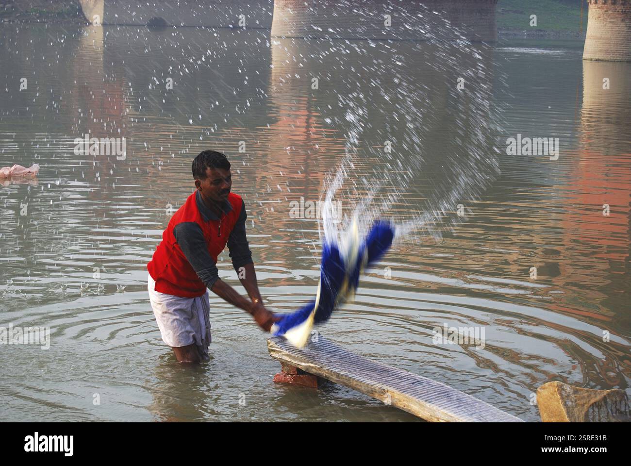 Washer man dhobi washing clothes splash of water drops in air at bank ...