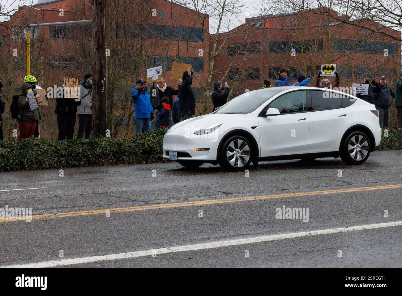 Portland, USA. 15th Feb, 2025. A Tesla drives past the demonstrators ...