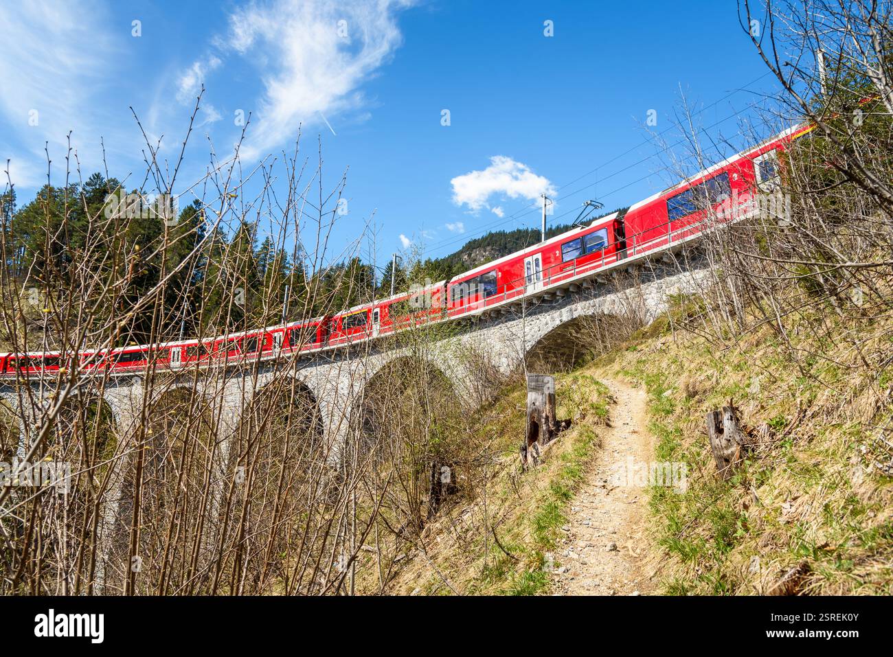 Narrow trail leading up to a stone railway viaduct crossed by a red ...