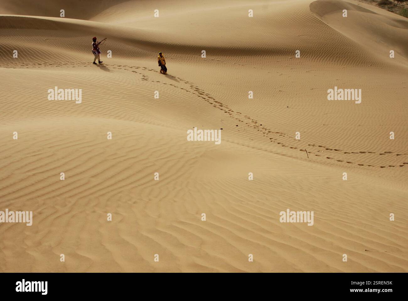 Rajasthani folk musician playing ravanhatta lady walking on sand dune ...