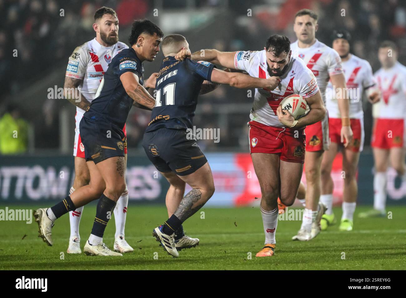 Alex Walmsley of St. Helens is tackled by Finley Yates of Salford Red ...