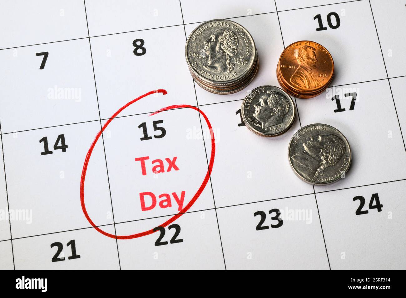 Tax Day April 15th circled in red ink on calendar with piles of coins ...