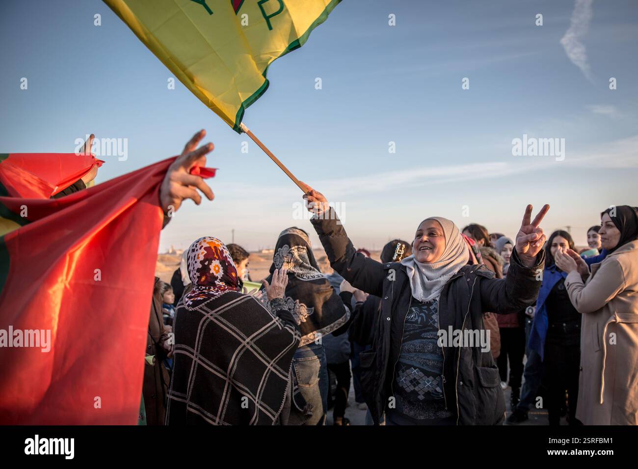 Hasaka, Syria. 15th Feb, 2025. A woman waves a YPG flag as friends and ...