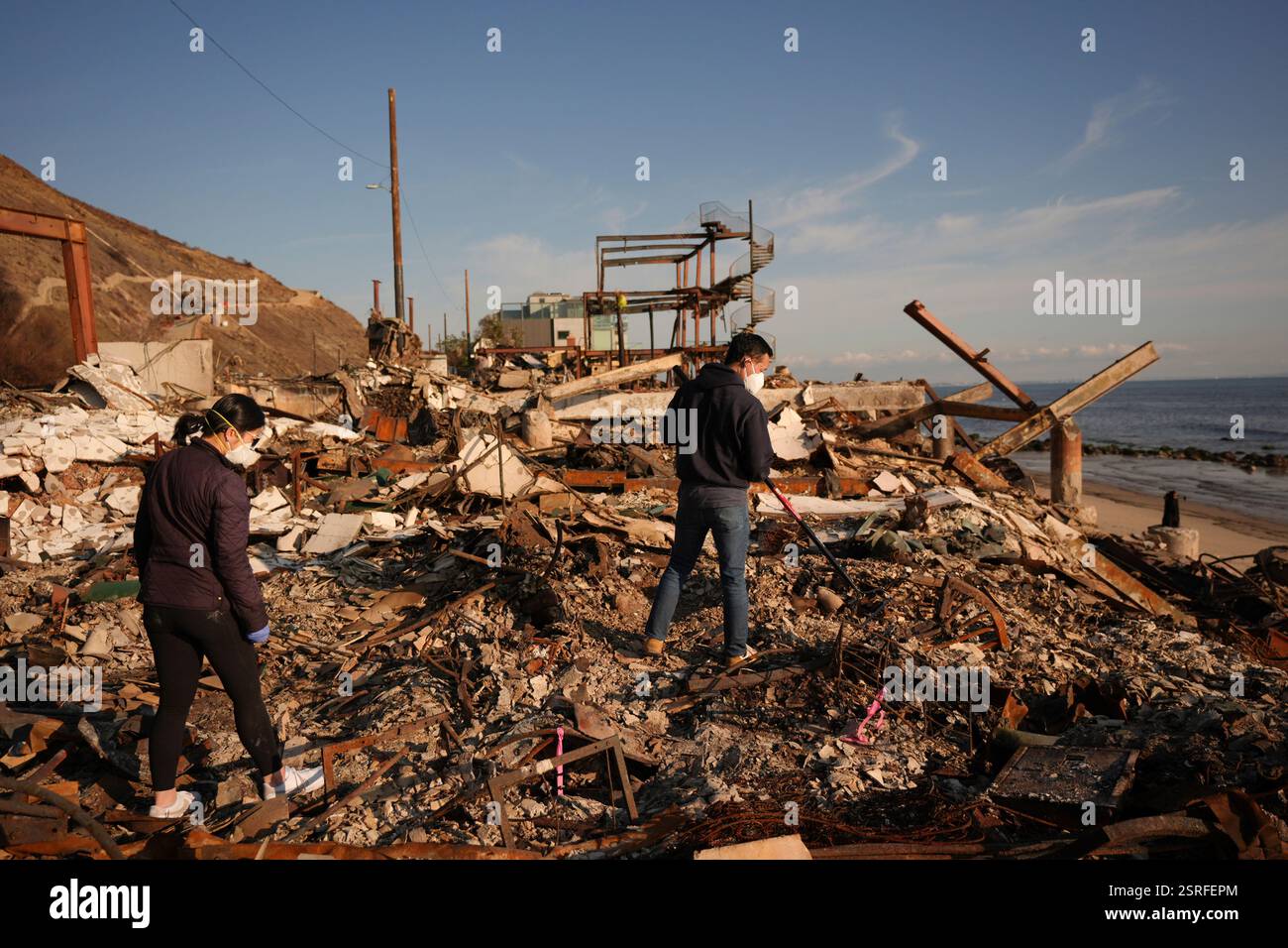 FILE - Tony Lai, center, rakes through the remains of his fire-ravaged ...