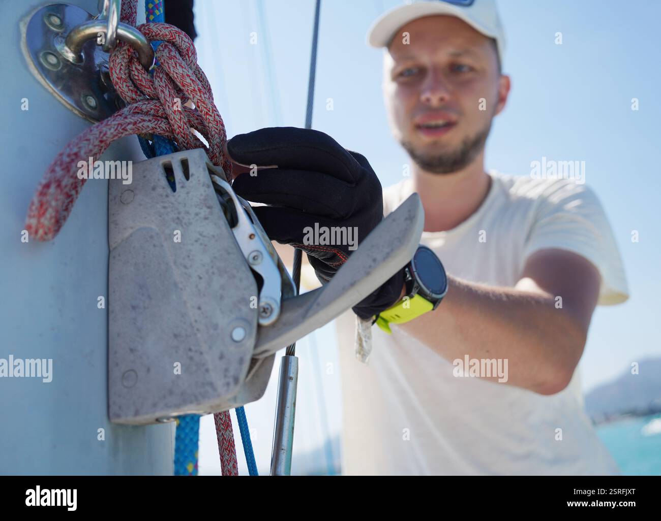 Male captain on deck of sailboat opening sails pulling the rope Stock ...
