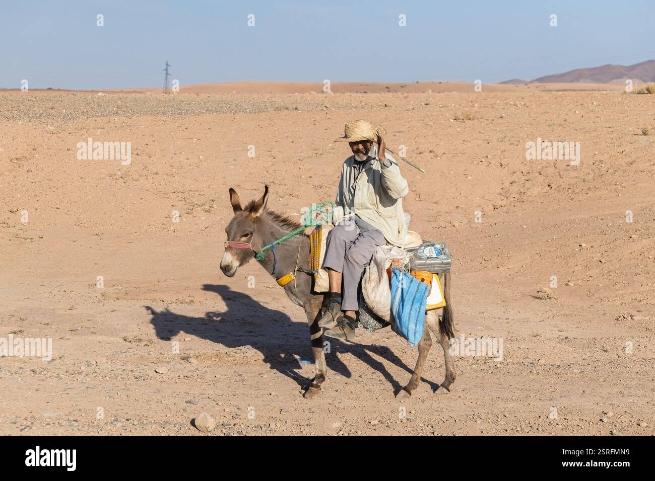Old Moroccan man riding the donkey in the desert valley on the road in ...