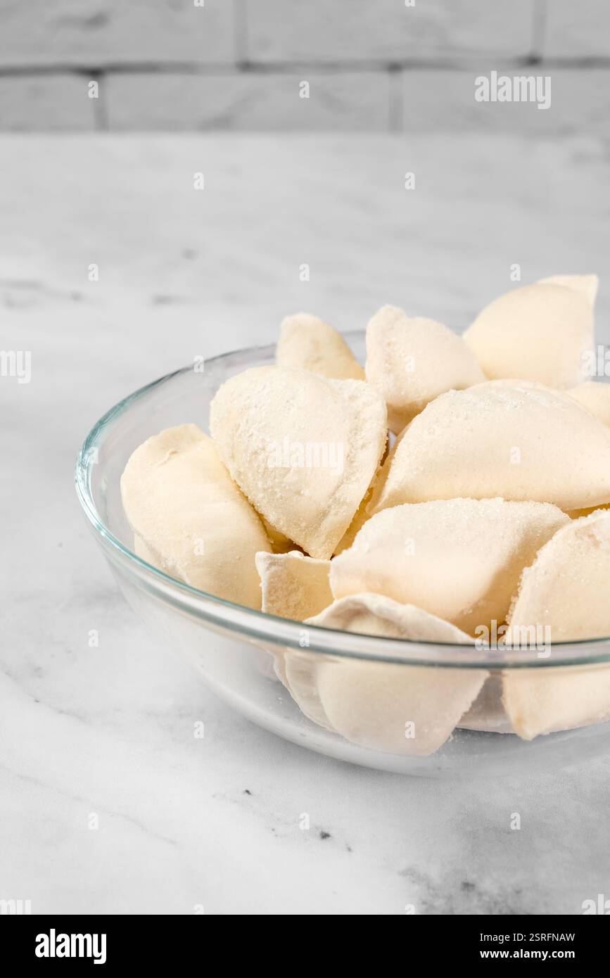 A bowl of frozen dumplings on a light background. Frozen semi finished ...