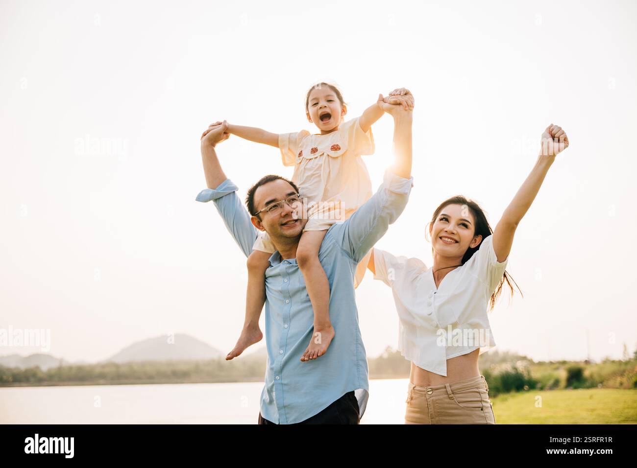 Asian family child girl piggyback riding back on father raising hands ...