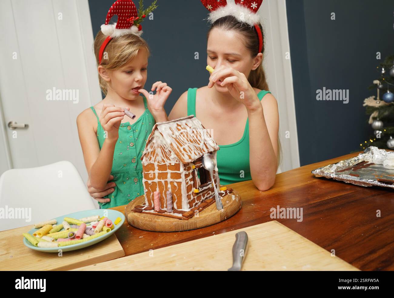 Mother and daughter at the table cooking gingerbread house for ...