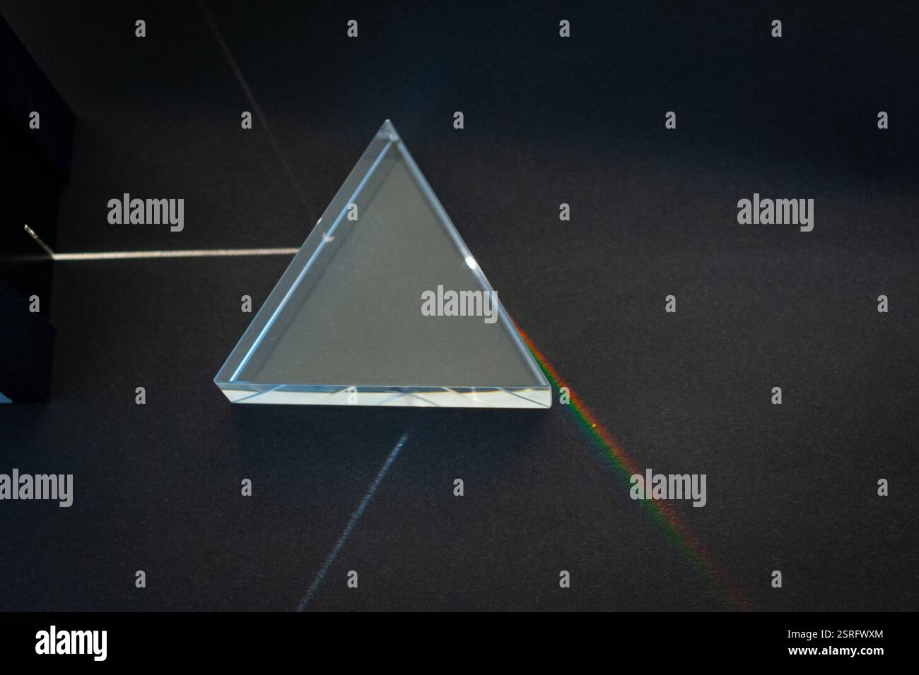 A beam of light is refracted in a triangular piece of glass creating a ...