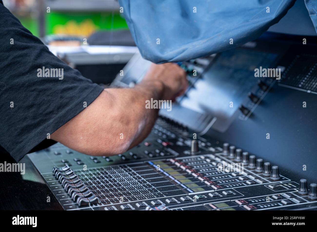The arm of a sound engineer working on a mixing board. The whole set is ...
