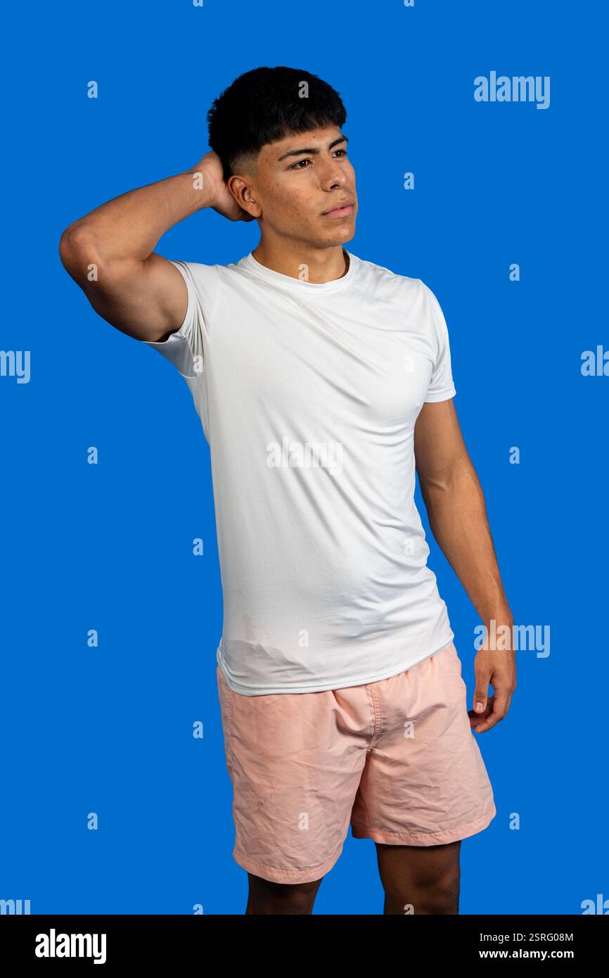 Young latino man wearing white t-shirt and pink shorts touching his ...