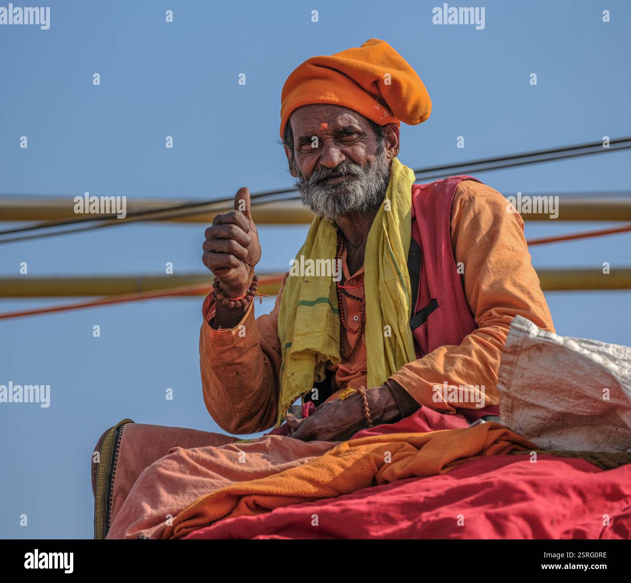 A Hindu sadhu in traditional orange attire sits atop an elephant ...