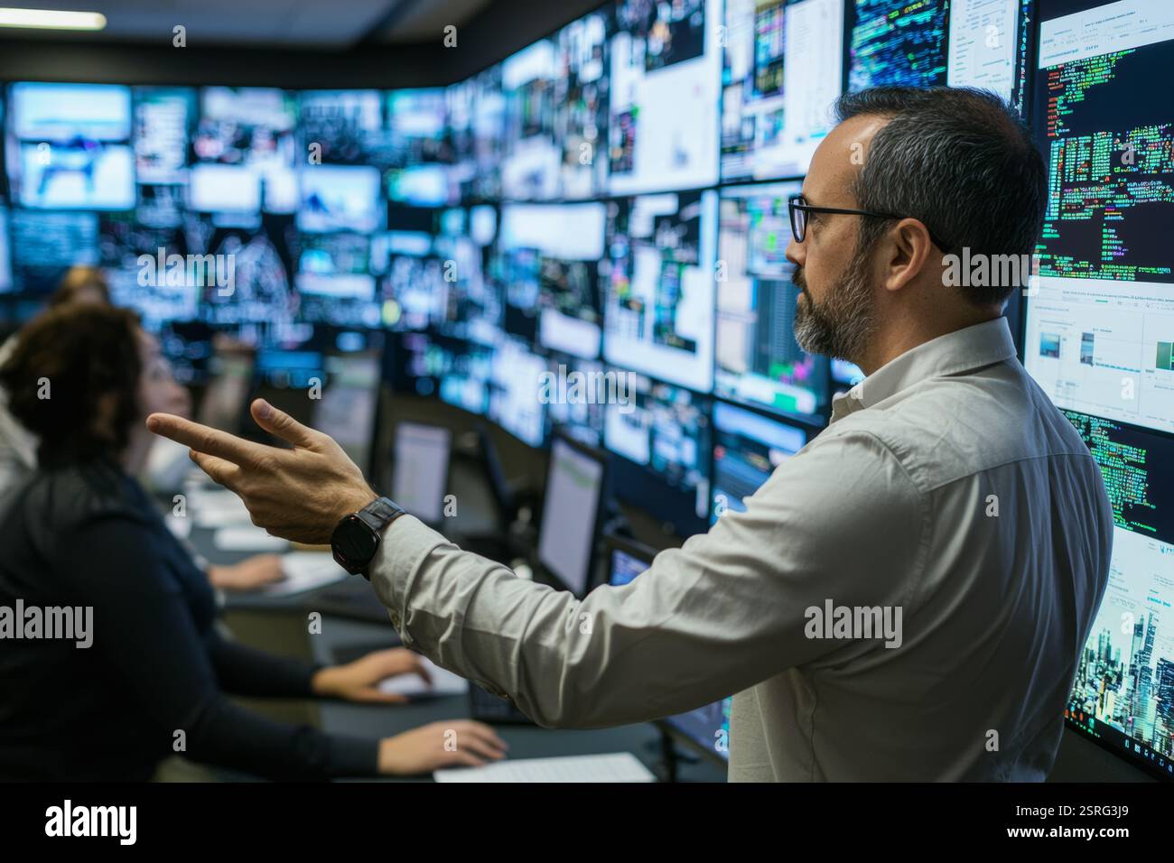 A focused professional gestures while explaining data insights in a modern control room filled ...