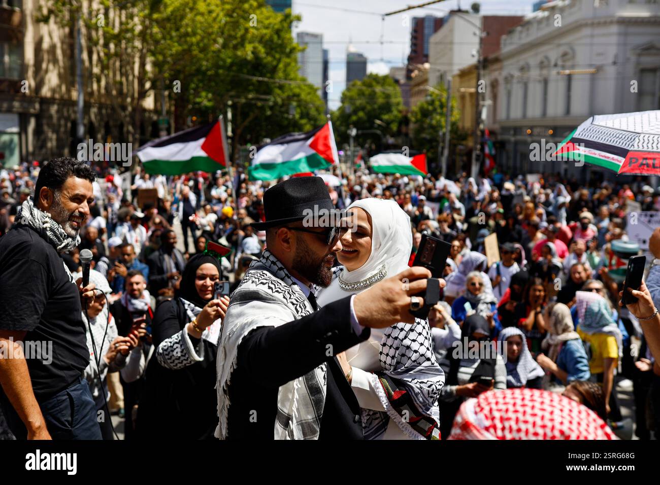A married couple takes a selfie with their phone, while hundreds of ...