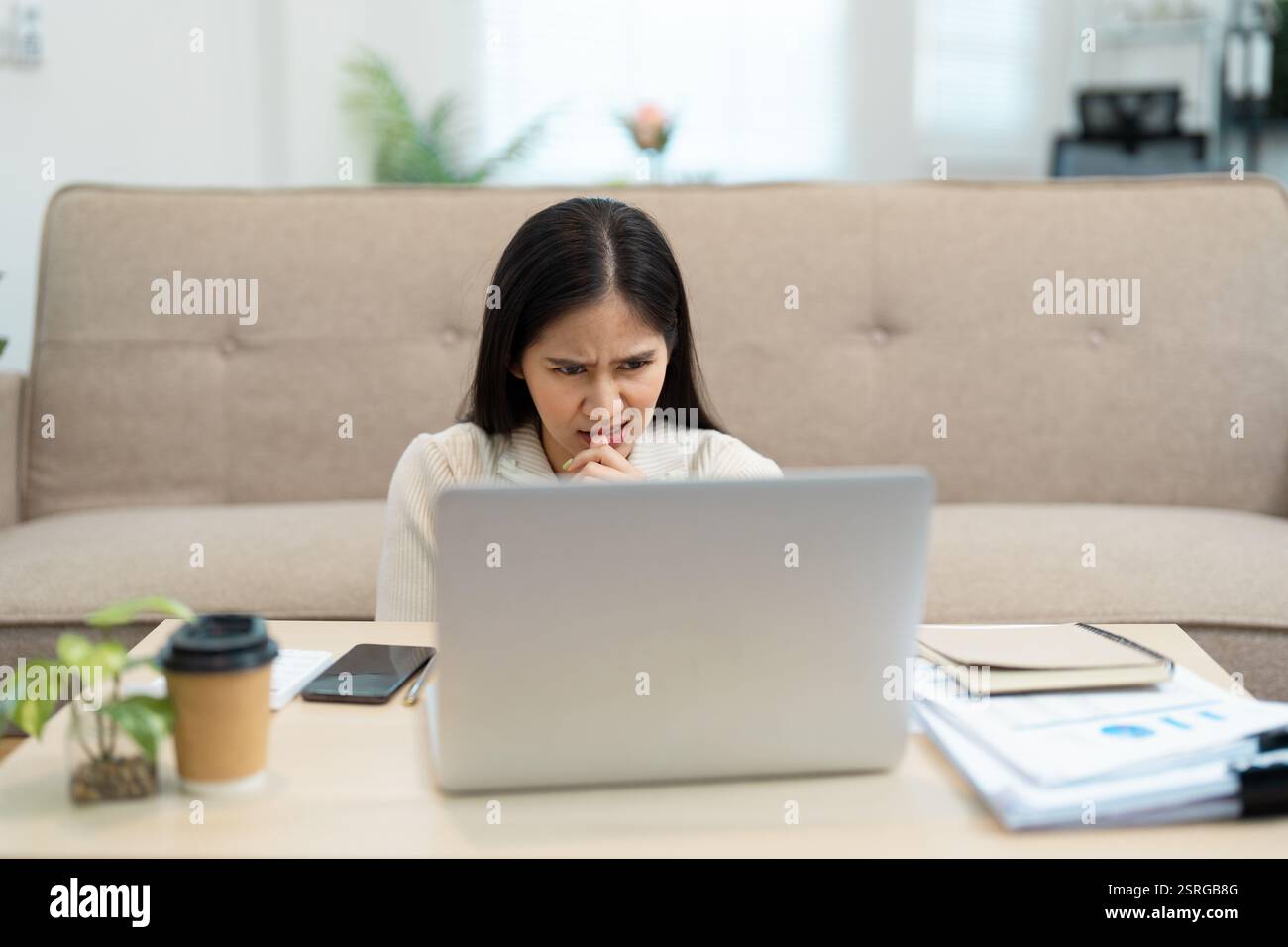 Concerned woman biting nails while working on laptop at home Stock ...
