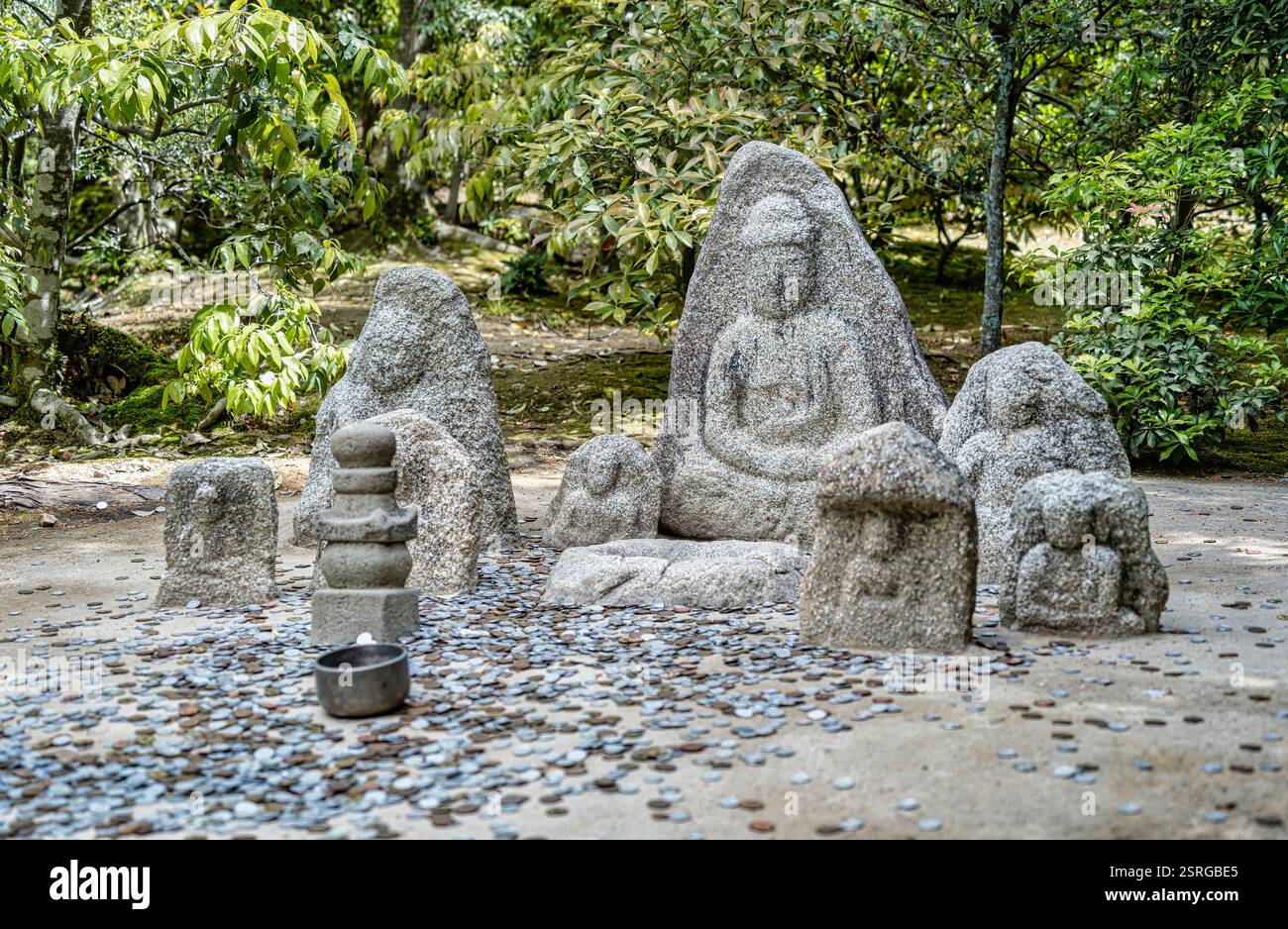 Japanese small jizo statues and many coins on the ground for good luck ...