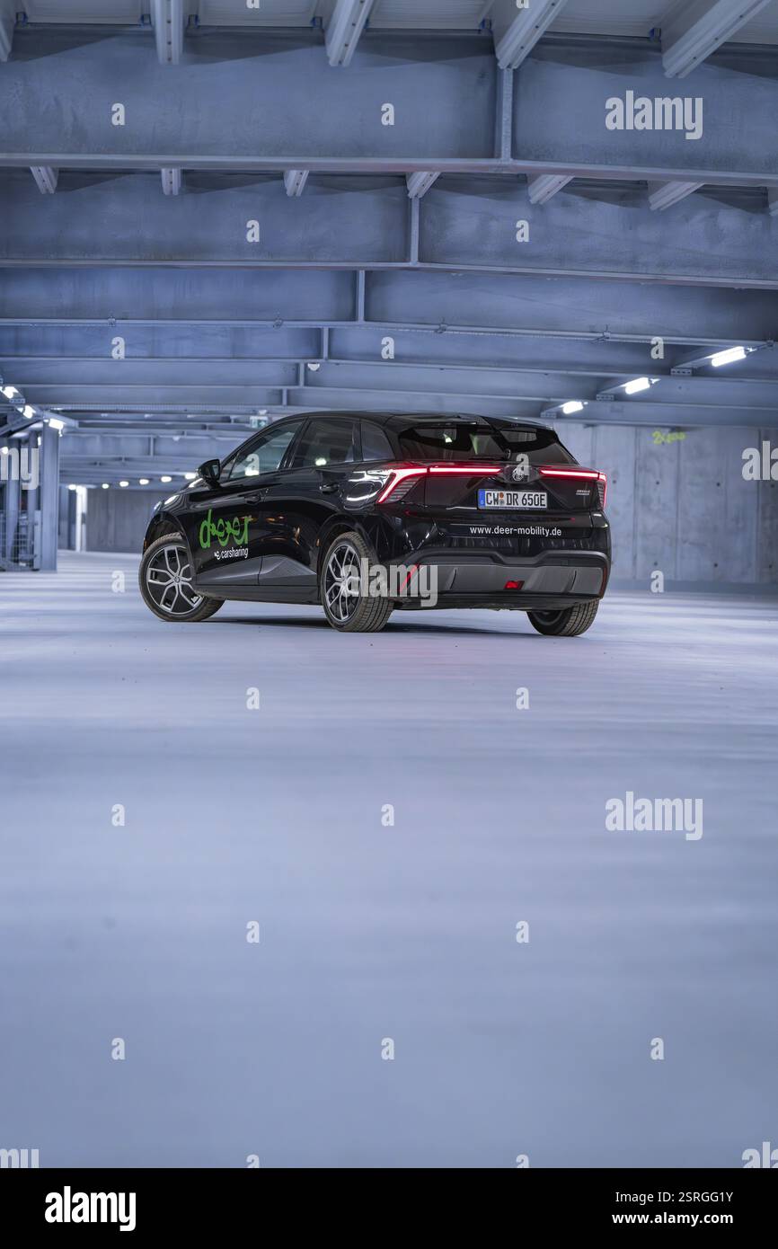 Black car from behind in an empty car park at night, e-car sharing ...
