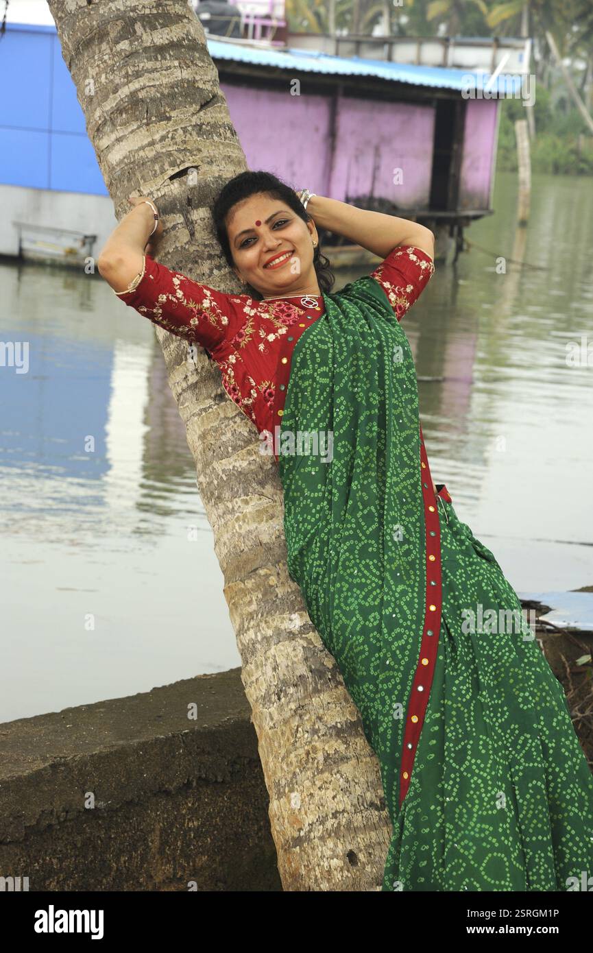 Woman standing leaning palm tree, isola di cocco, Kerala, India, Asia ...