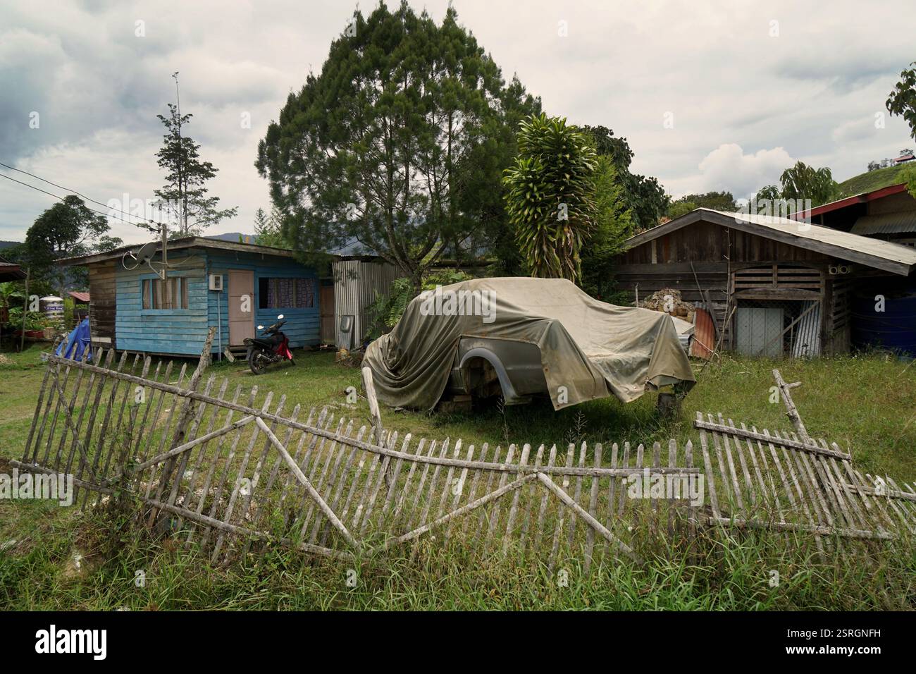 A still life of wooden houses and a car in Bario, evoking the rugged ...
