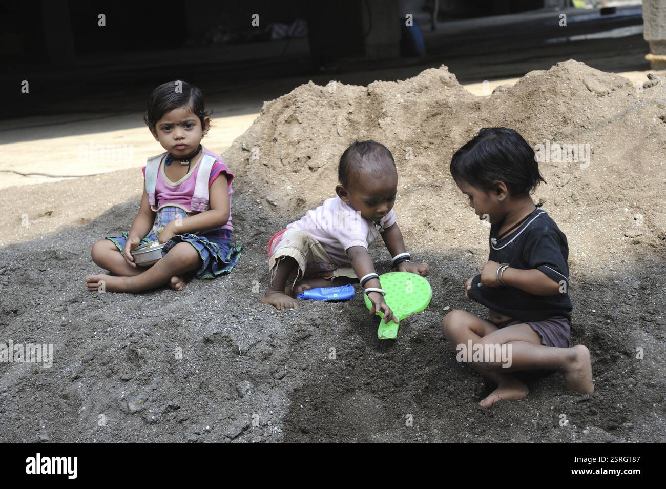 Children playing in sand at building construction site, Pune ...