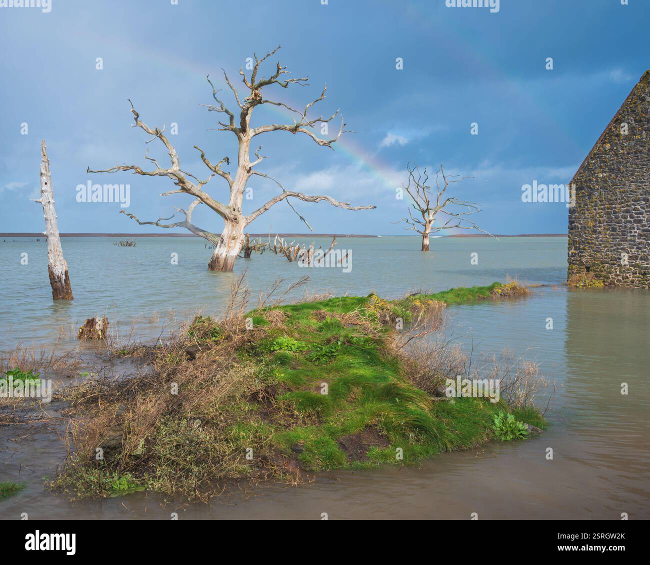 High spring tide flooding the salt marshes with a rainbow across the ...