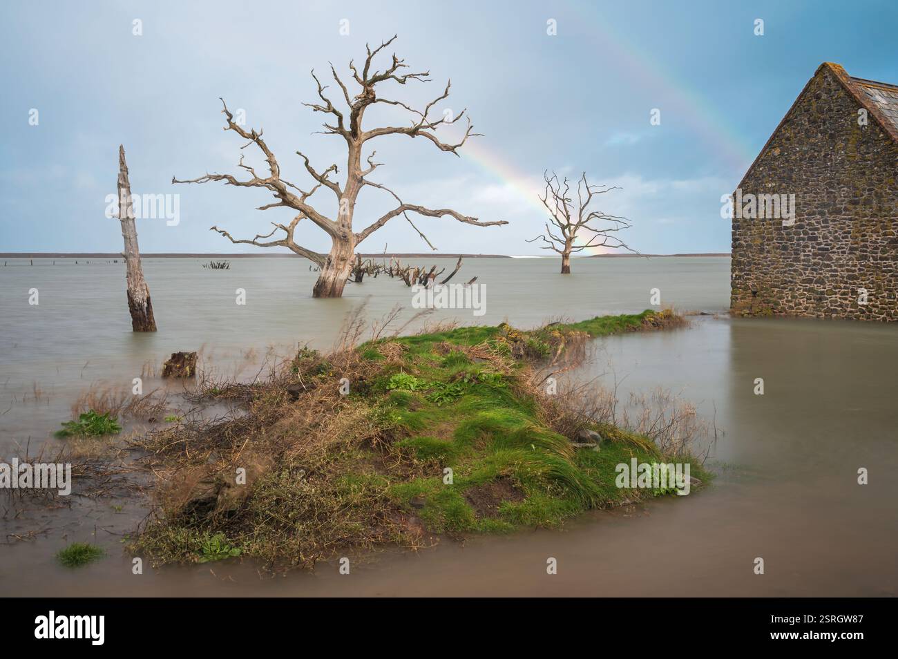 High spring tide flooding the salt marshes with a rainbow across the ...
