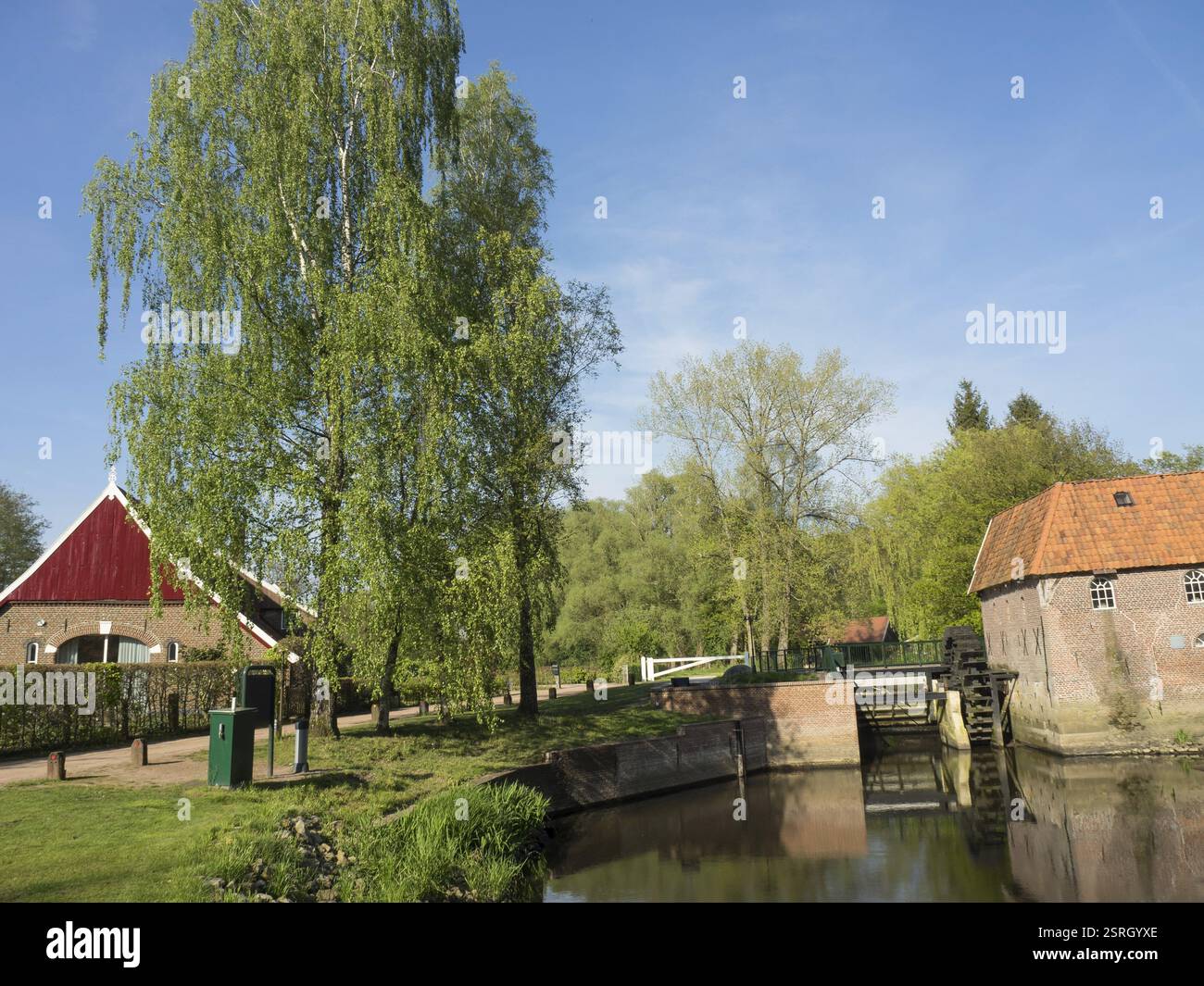 Rural scenery with river, bridge, and buildings on a clear day ...
