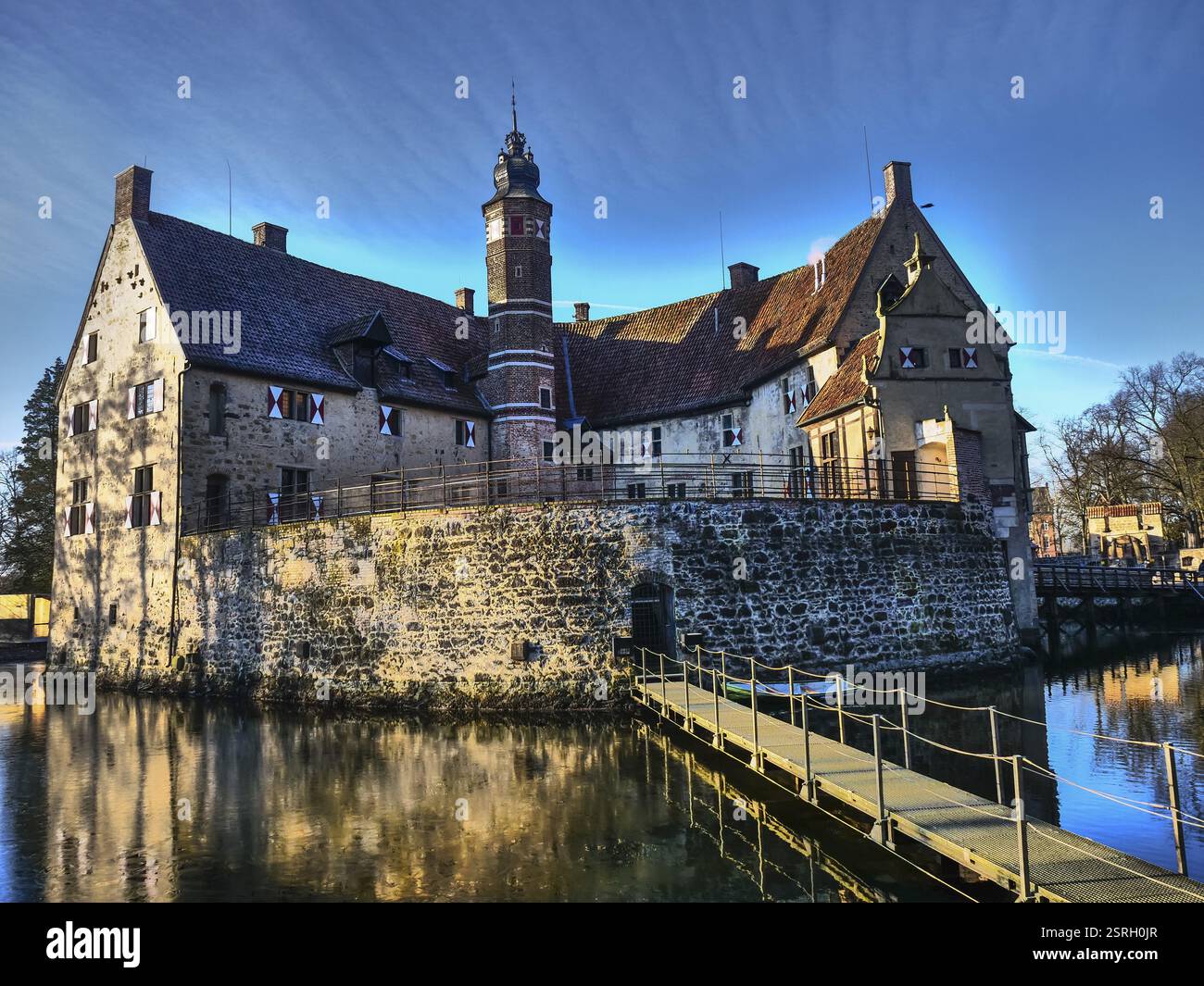 An impressive medieval castle with a moat and a bridge under a clear ...