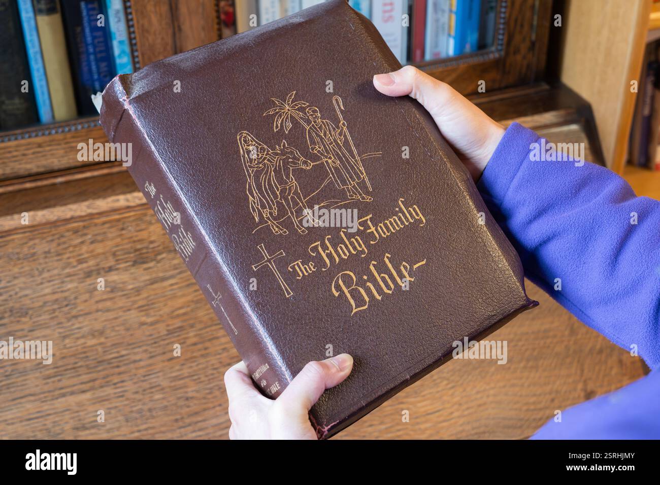 Woman holding a large copy of the Holy Family Bible with an ...