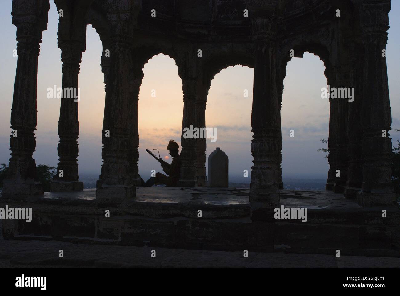 Folksinger playing ravanhatta at sunrise in cenotaph, Rajasthan, India ...