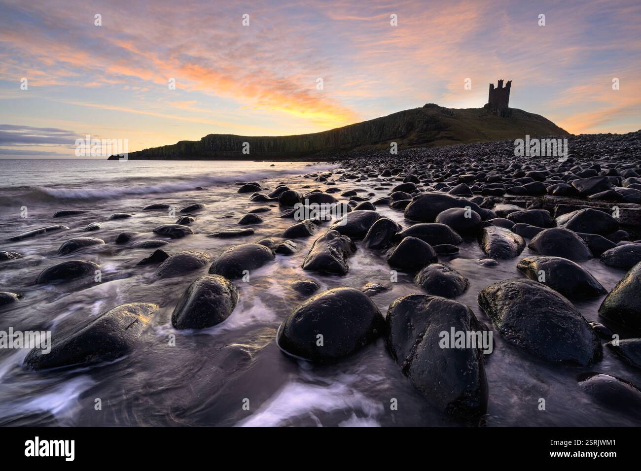 Rocky beach with Dunstanburgh Castle seen from Embleton Bay ...