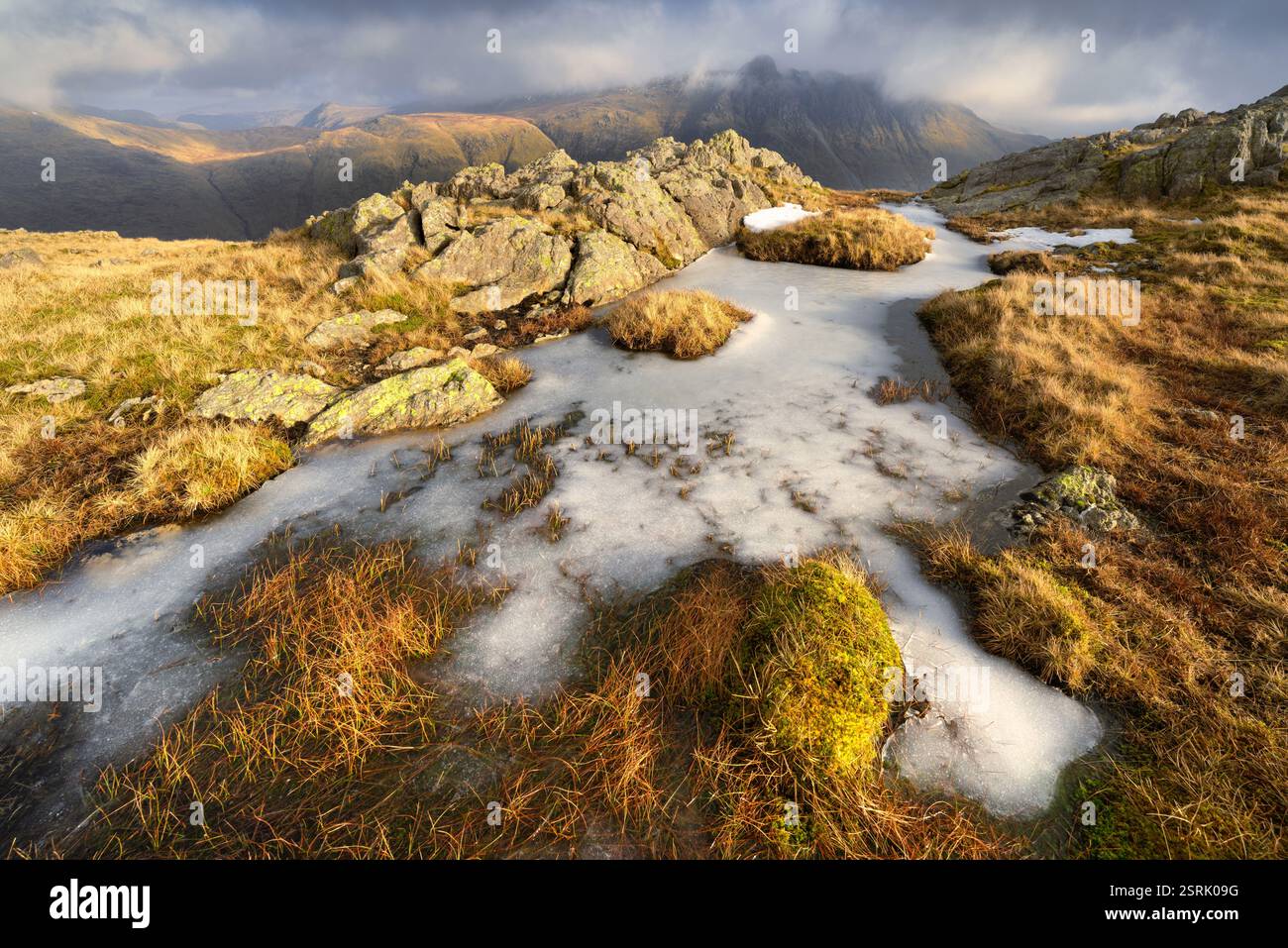 Frozen tarn on winter afternoon with grand view of dramatic Lake ...