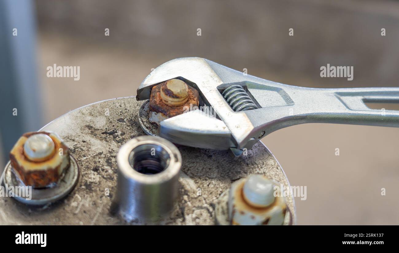Adjustable wrench used to loosen a rusty bolt on a metal surface Stock ...