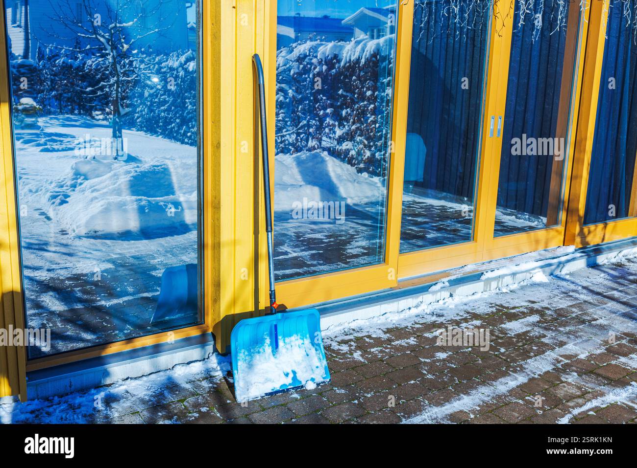 Snow shovel leaning against panoramic glass windows of modern villa ...