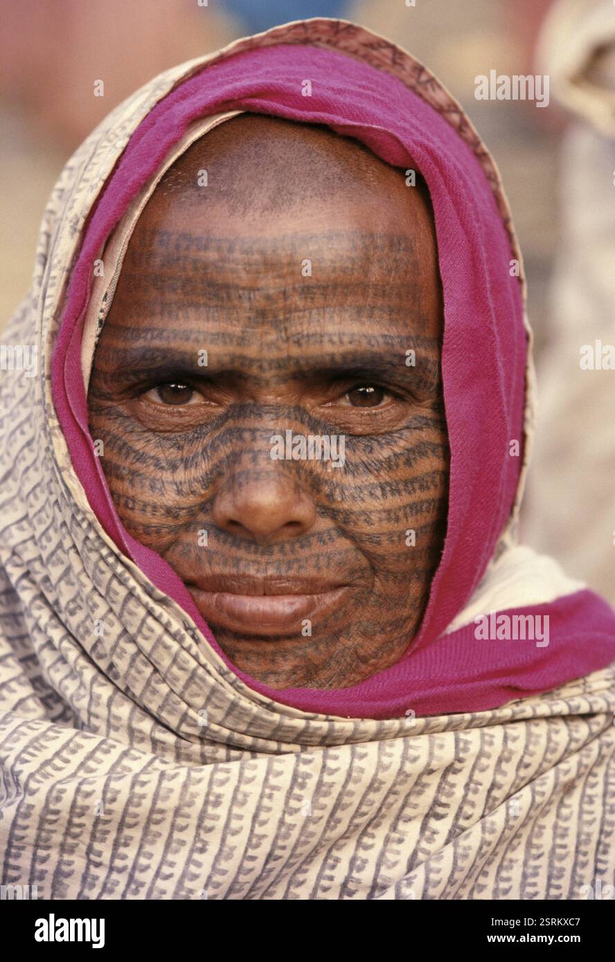 Tattooed face of Ramnaami ascetic woman, against black and white hand ...