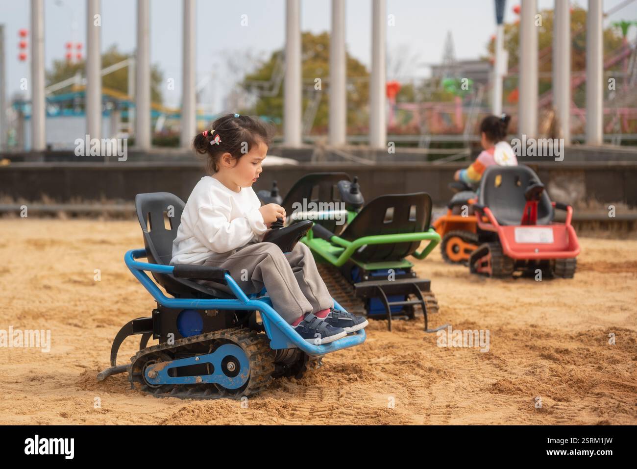 A four years old multiracial girl driving toy car with caterpillar ...