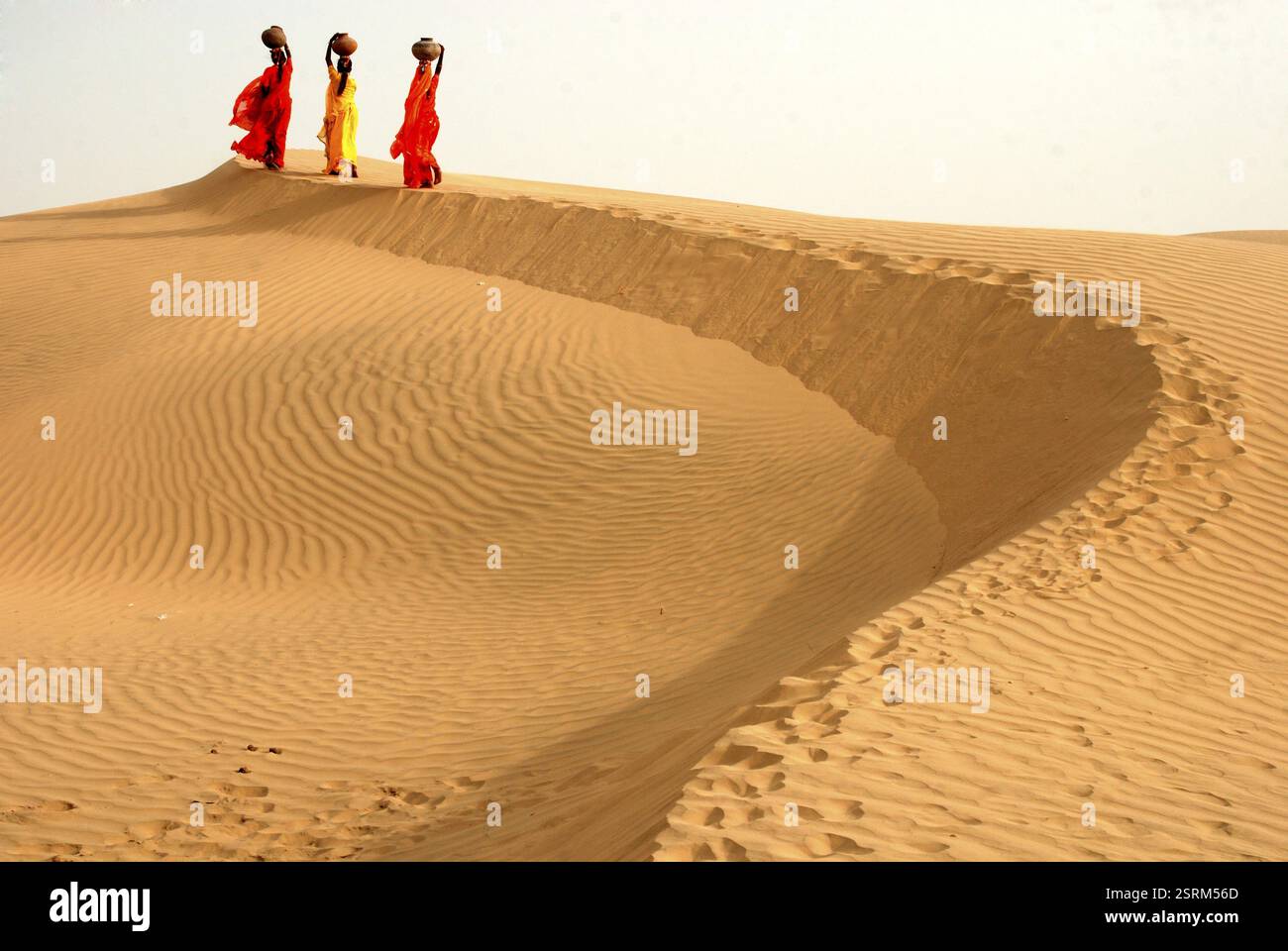 Rajasthani women with pitchers on head walking on sand dune of Khuri ...