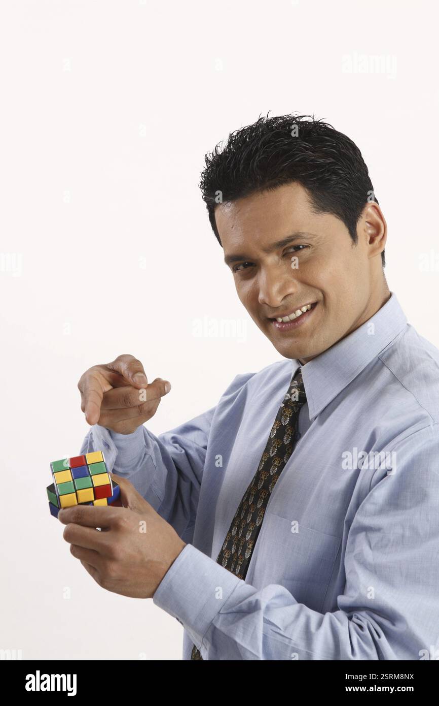 Businessman holding Rubik cube in one hand and pointing index finger MR ...