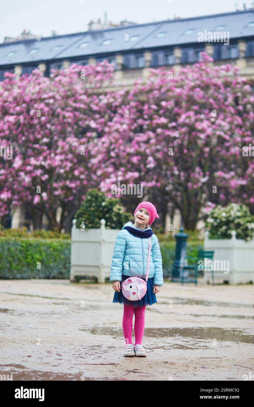 Adorable preschooler girl enjoying pink magnolias in full bloom on a ...