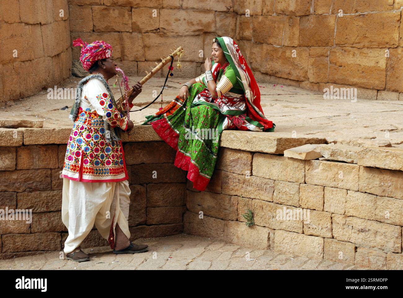 Rajasthani folk musician playing ravanhatta with lady sitting on steps ...