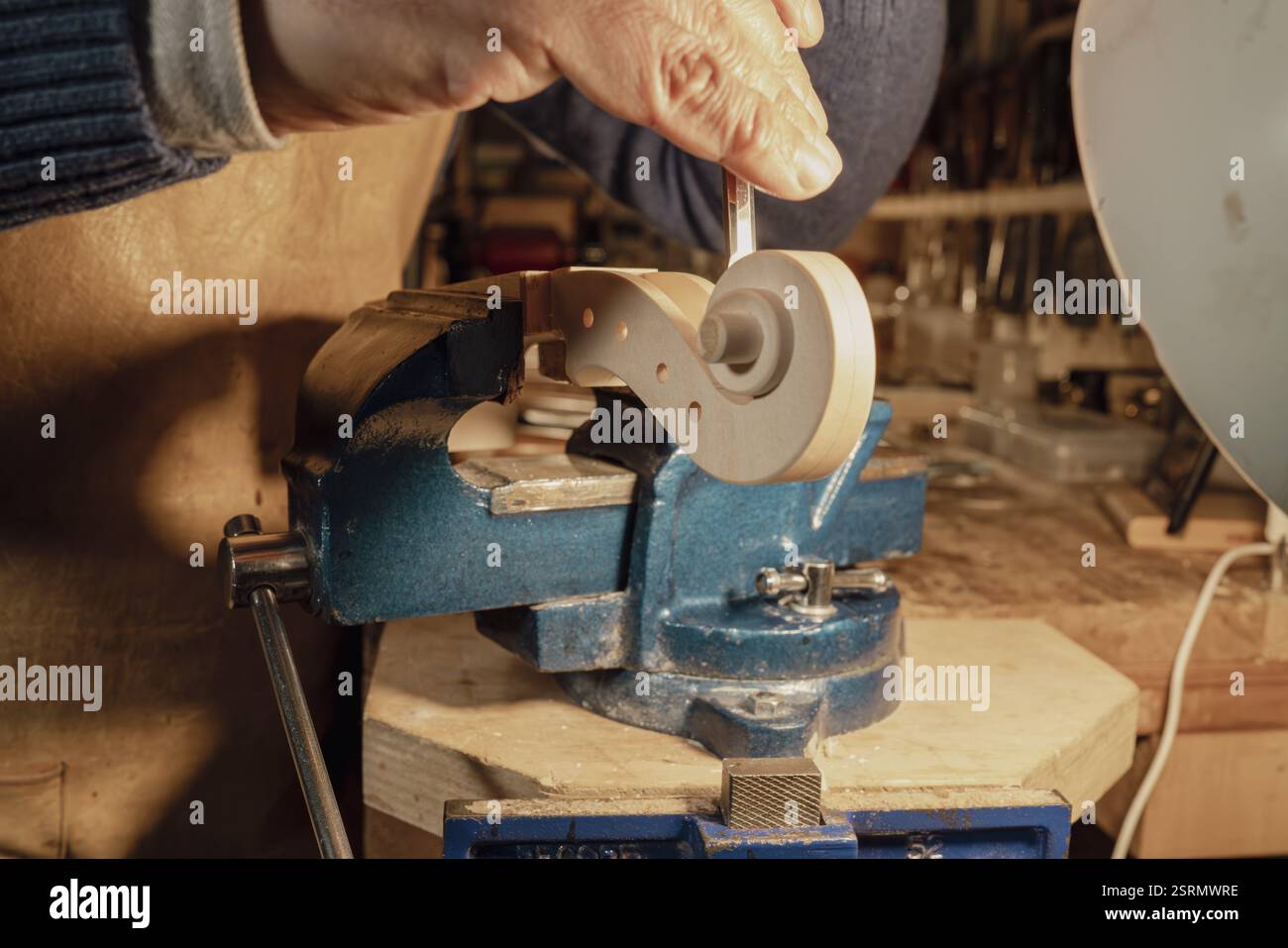Italian luthier is meticulously shaping the scroll of a violin using a ...