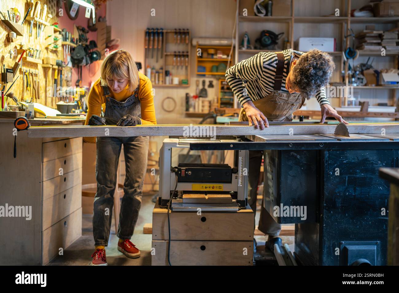 Carpentry colleagues handle circular saw station, measure wood beam ...