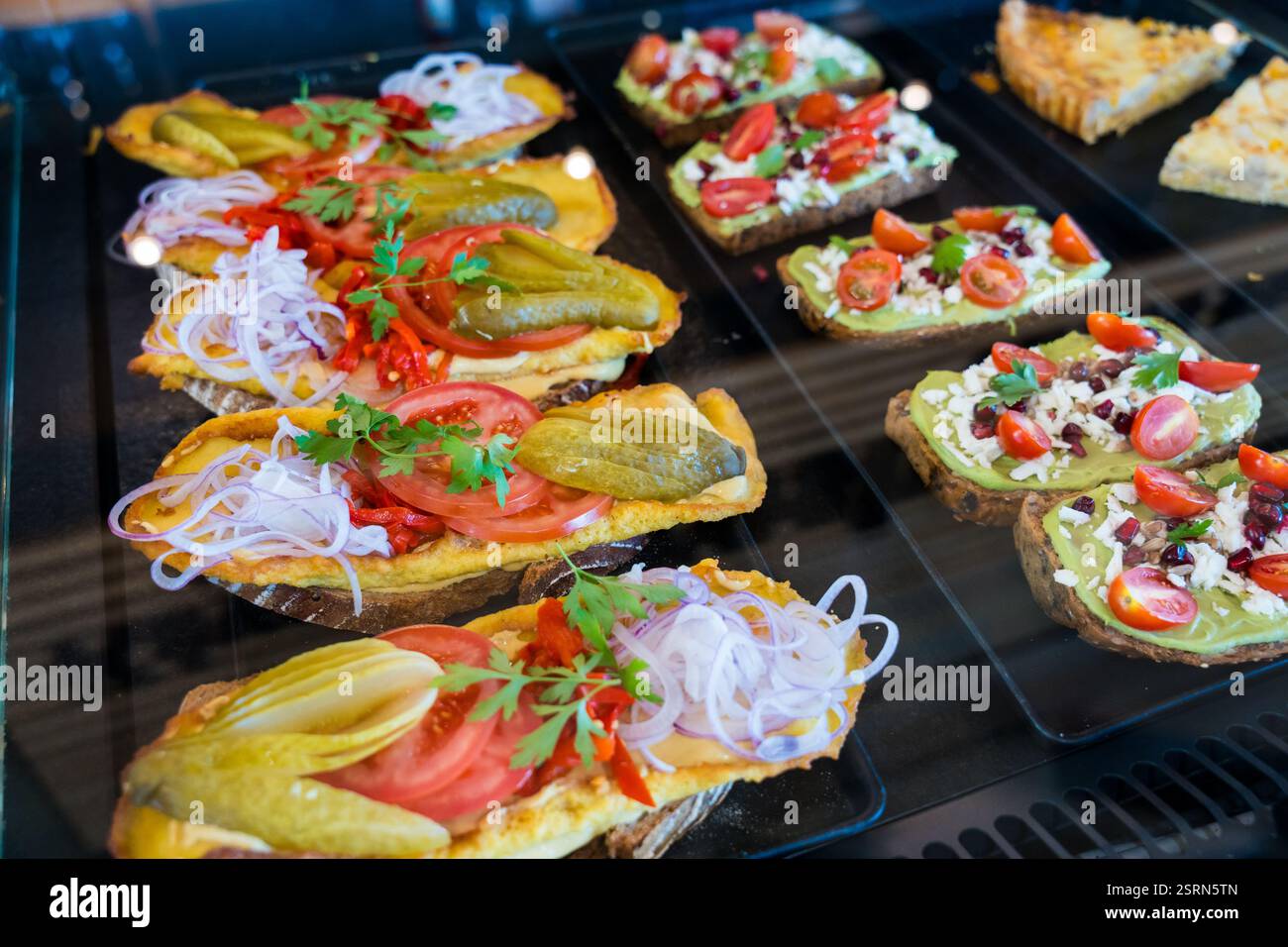 Assorted open-faced sandwiches with fresh toppings in a display case ...