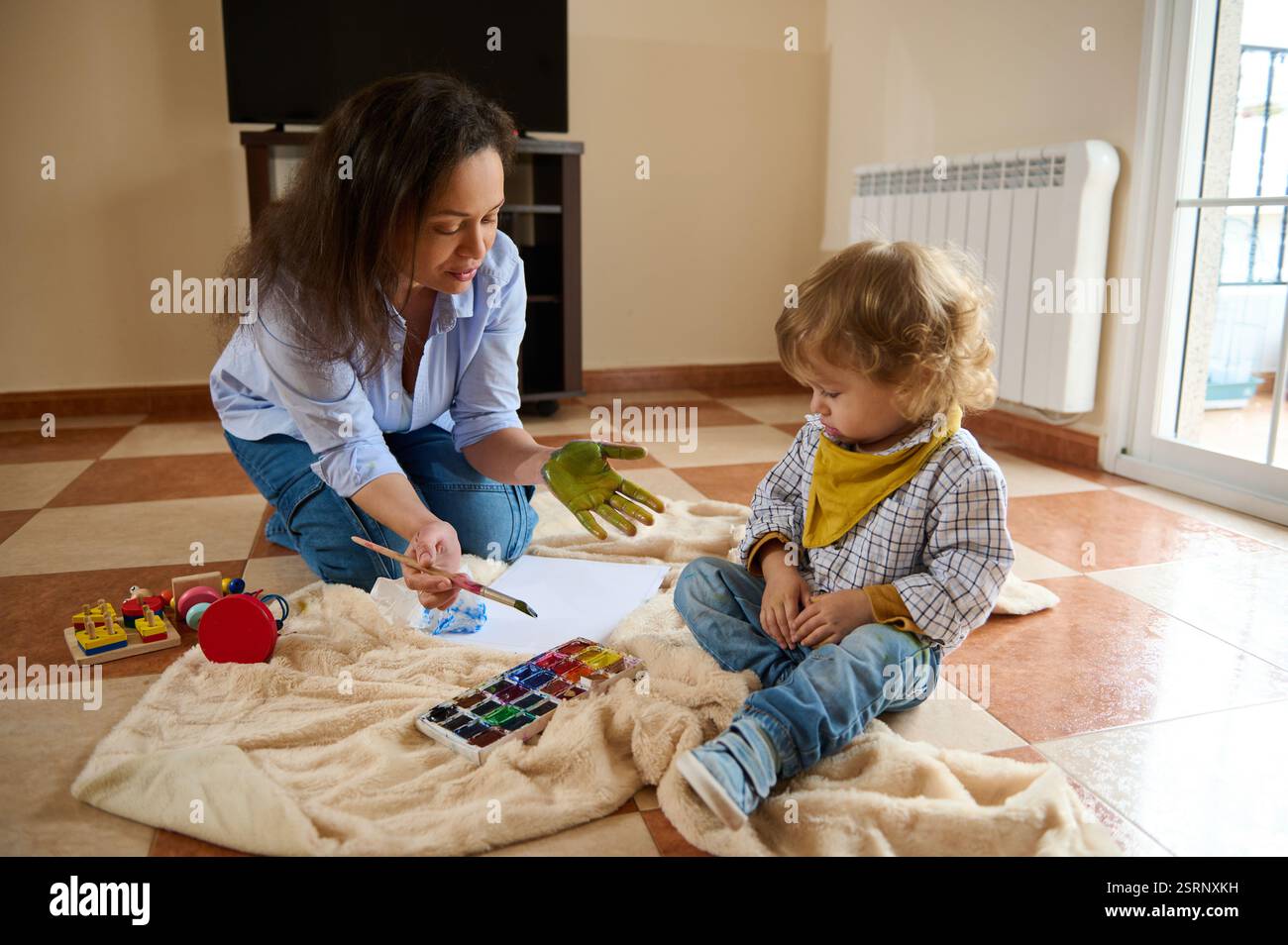 Mother and child share a joyful moment painting together on the floor ...