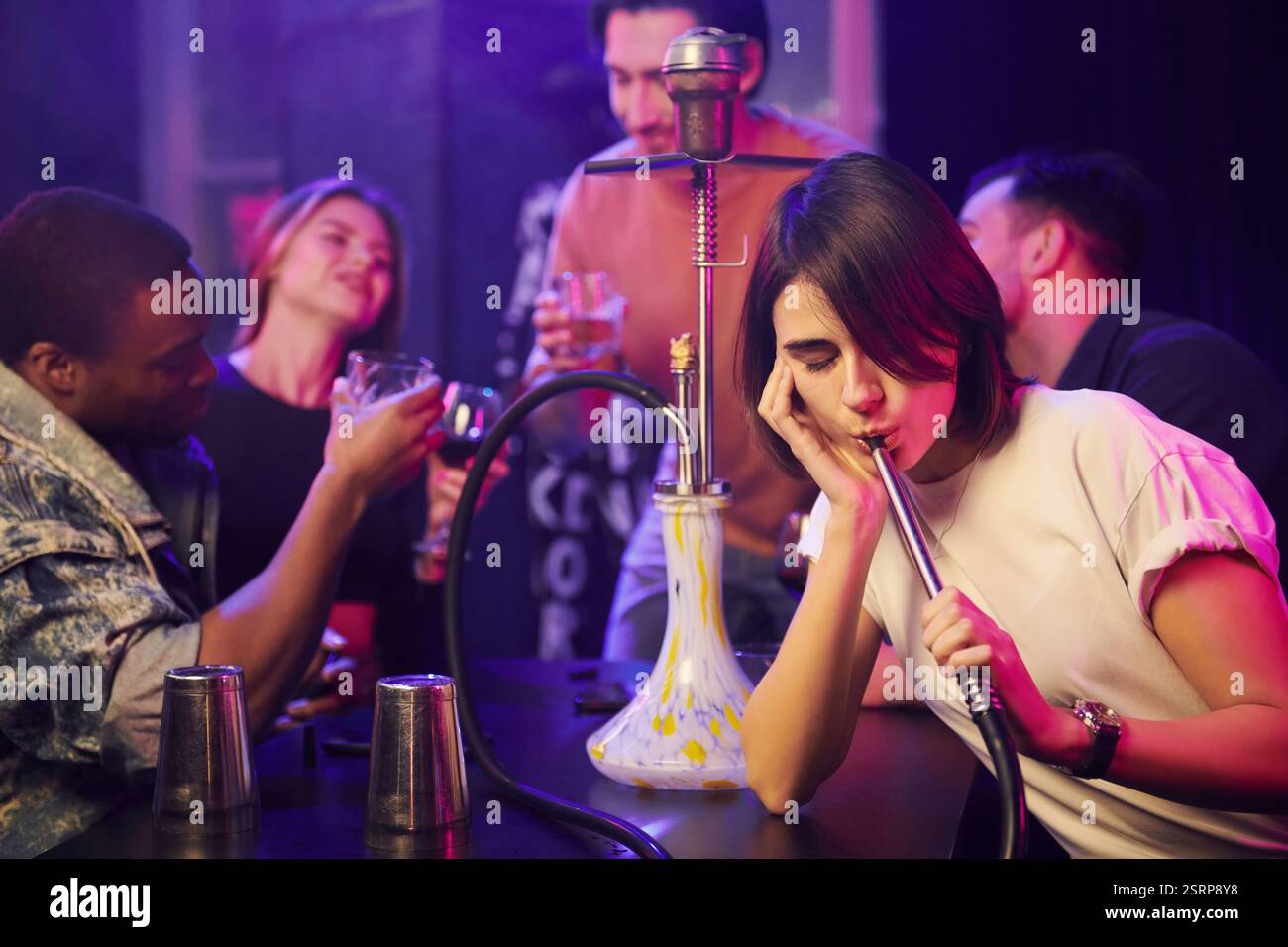 Woman smoking hookah. Group of friends having fun in the night club ...