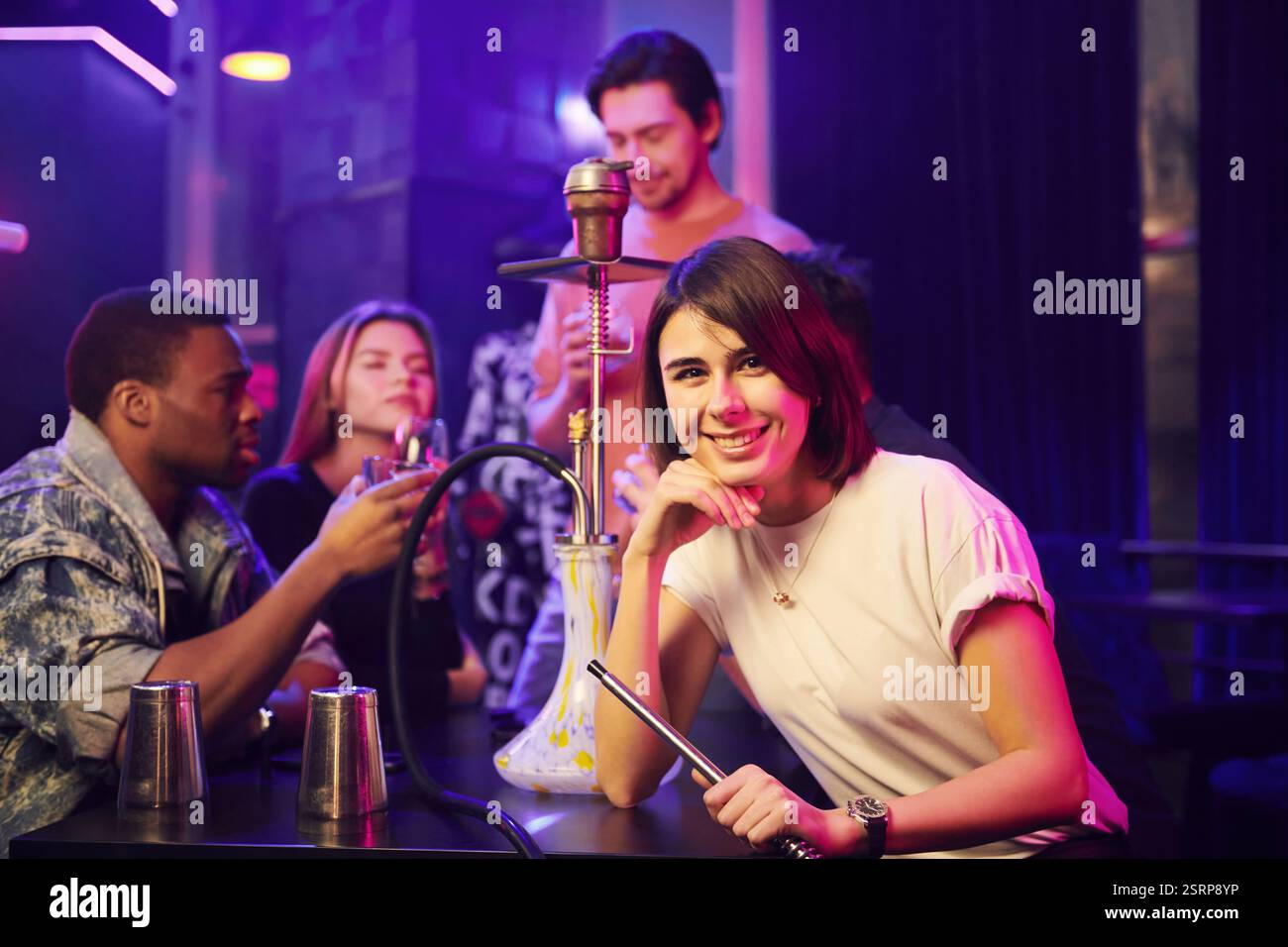 Woman smoking hookah. Group of friends having fun in the night club ...