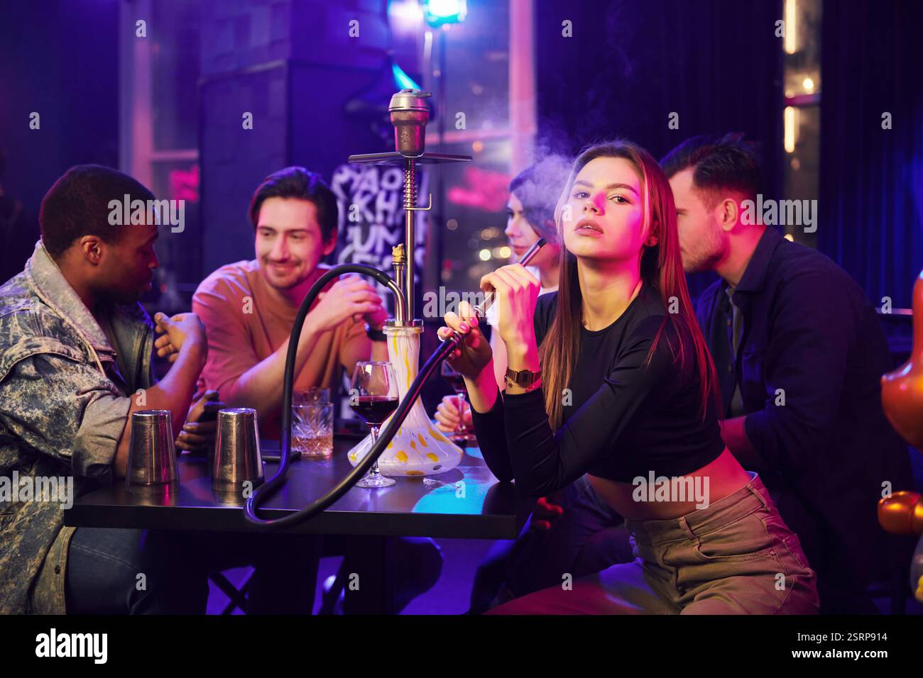 Woman smoking hookah. Group of friends having fun in the night club ...